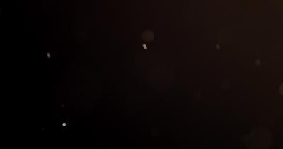 Bright golden particles glowing and floating on dark background in 4K ...