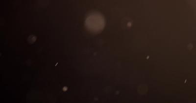 Bright golden particles glowing and floating on dark background in 4K ...